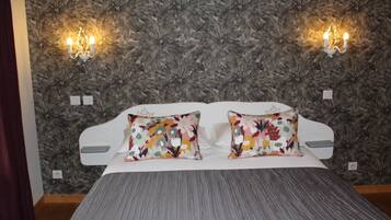 Quarto com uma cama, duas luminárias na parede e um papel de parede estampado com flores.