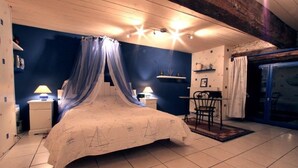 Quarto com cama de dossel, duas mesas de cabeceira com luminárias, uma cadeira e vista para o exterior através de uma porta de vidro.
