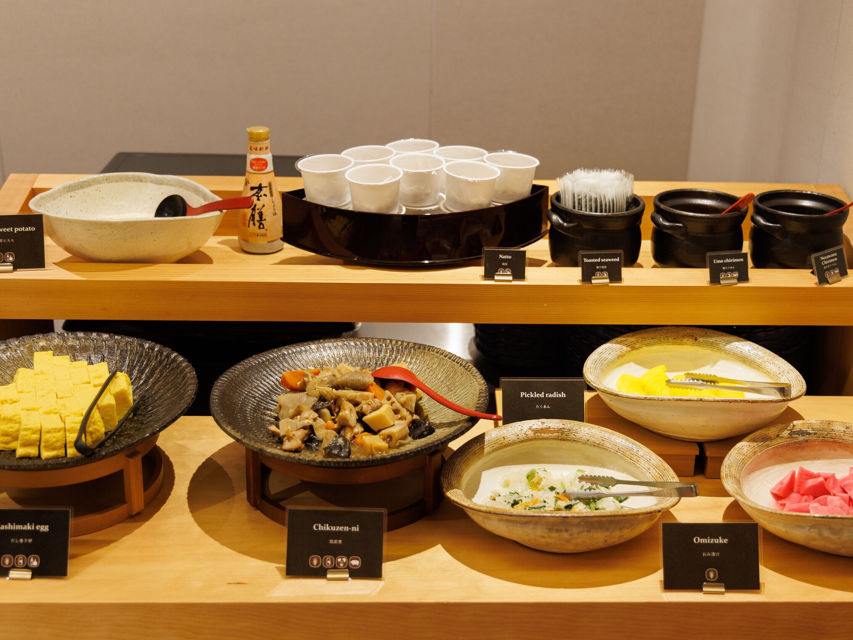 Buffet com diversos pratos, incluindo rabanete em conserva, chikuzen-ni e omizuke.