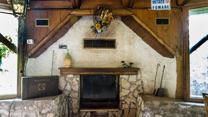 Uma lareira de pedra rústica com um parapeito de madeira, um rádio antigo e um aviso proibindo o fumo.