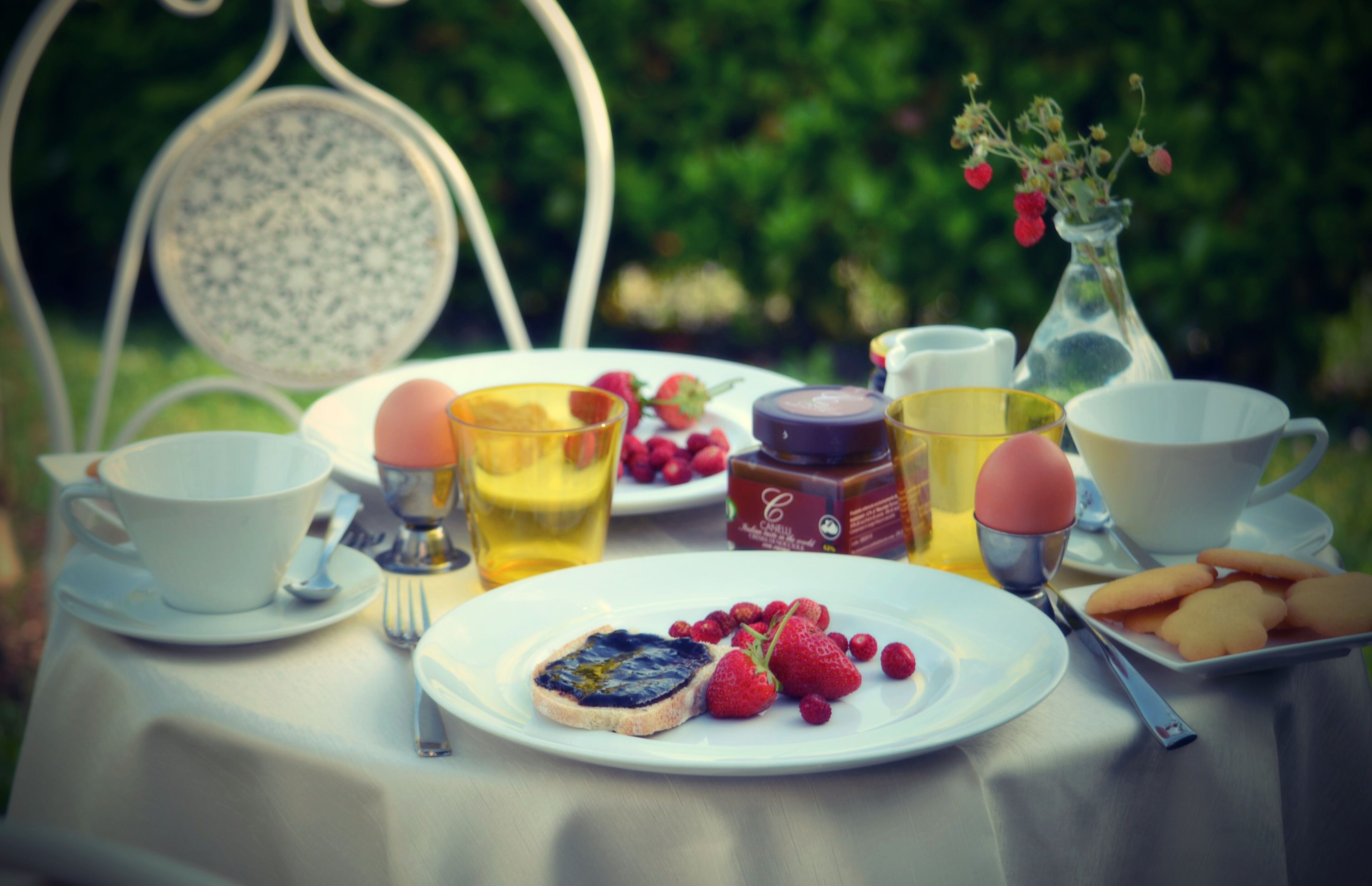 Uma mesa posta com itens de café da manhã, incluindo torradas, morangos e biscoitos.
