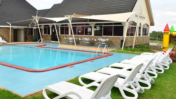 Piscina com espreguiçadeiras e área coberta com mesas e cadeiras.