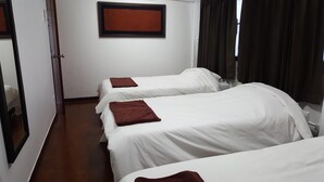 Quarto de hotel com duas camas de solteiro, um quadro na parede e uma porta para outro cômodo.