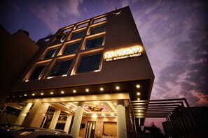 Um hotel com fachada moderna, janelas amplas e placa indicando que funciona como hotel, restaurante e espaço para banquetes.