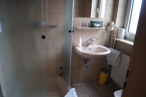 Chuveiro, toalhas de banho, sabonete, papel higiênico