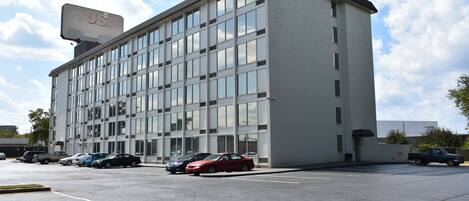 Um edifício moderno com um letreiro dos EUA, estacionamento e vários carros estacionados.