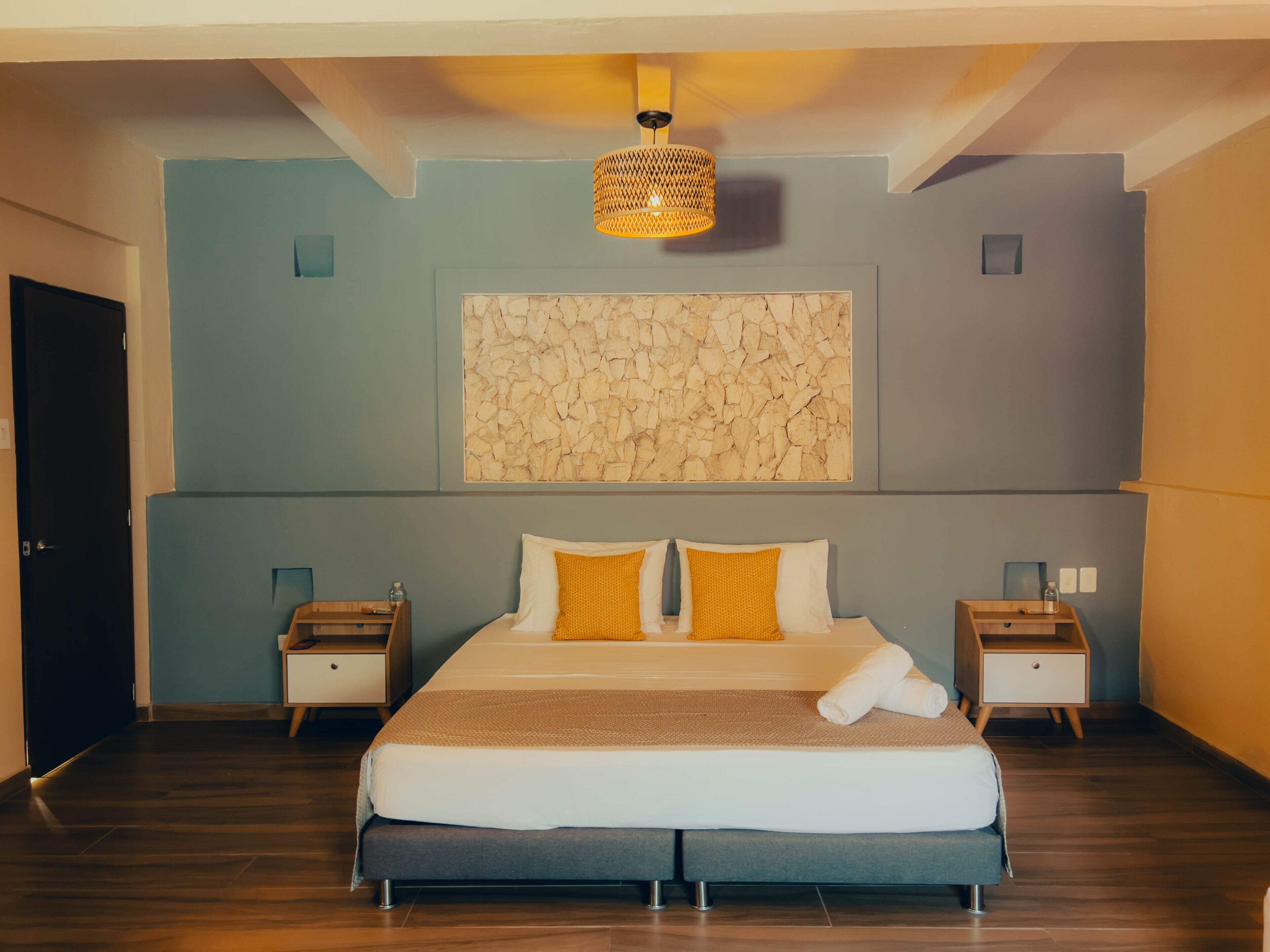 Quarto moderno com uma cama grande, duas mesas de cabeceira, uma obra de arte na parede e um lustre.