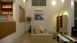 Uma sala de estar com sofá, mesa de centro, planta em vaso e estante.