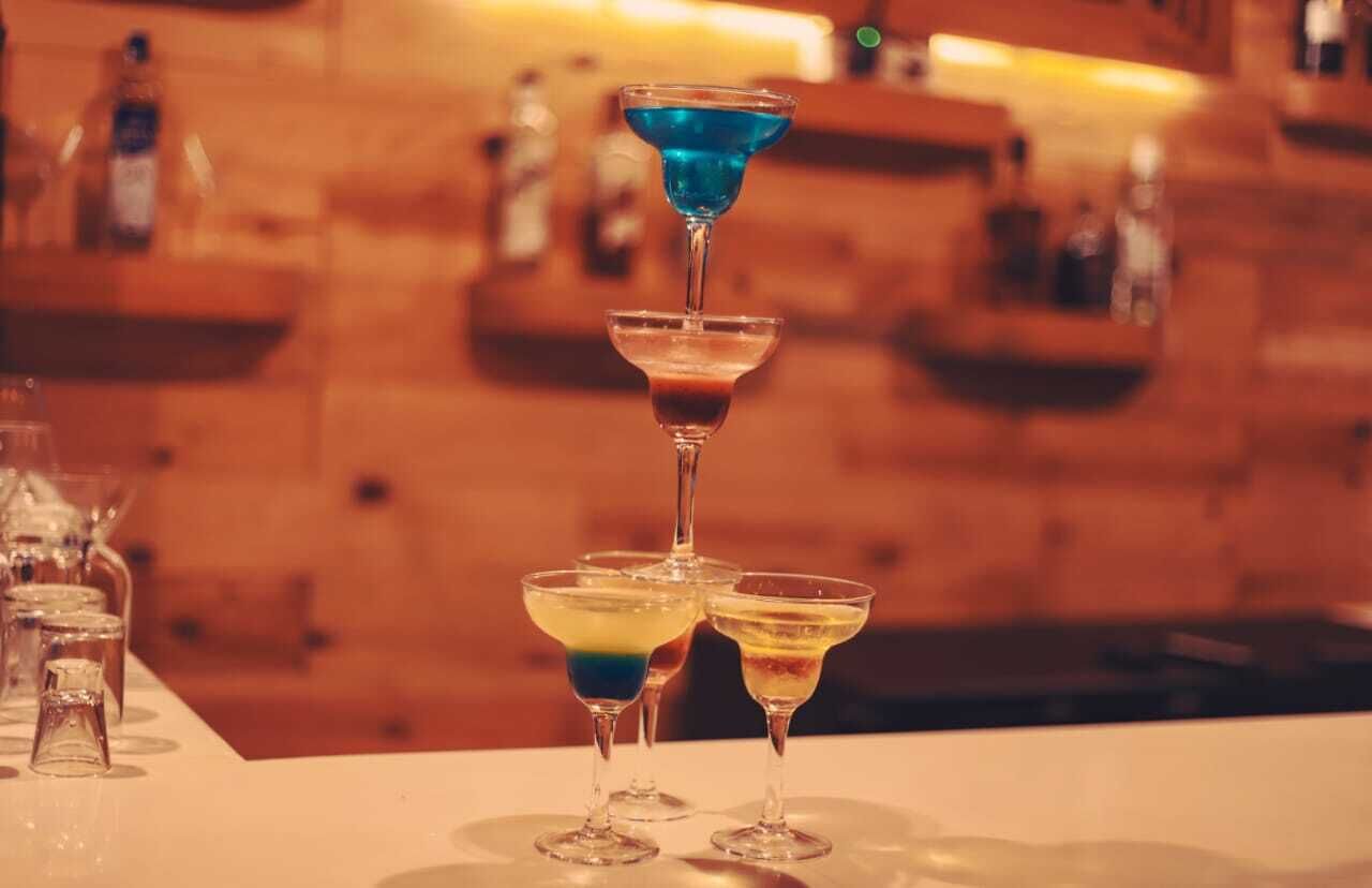 Um bar com fundo de madeira e diversos copos em um balcão.