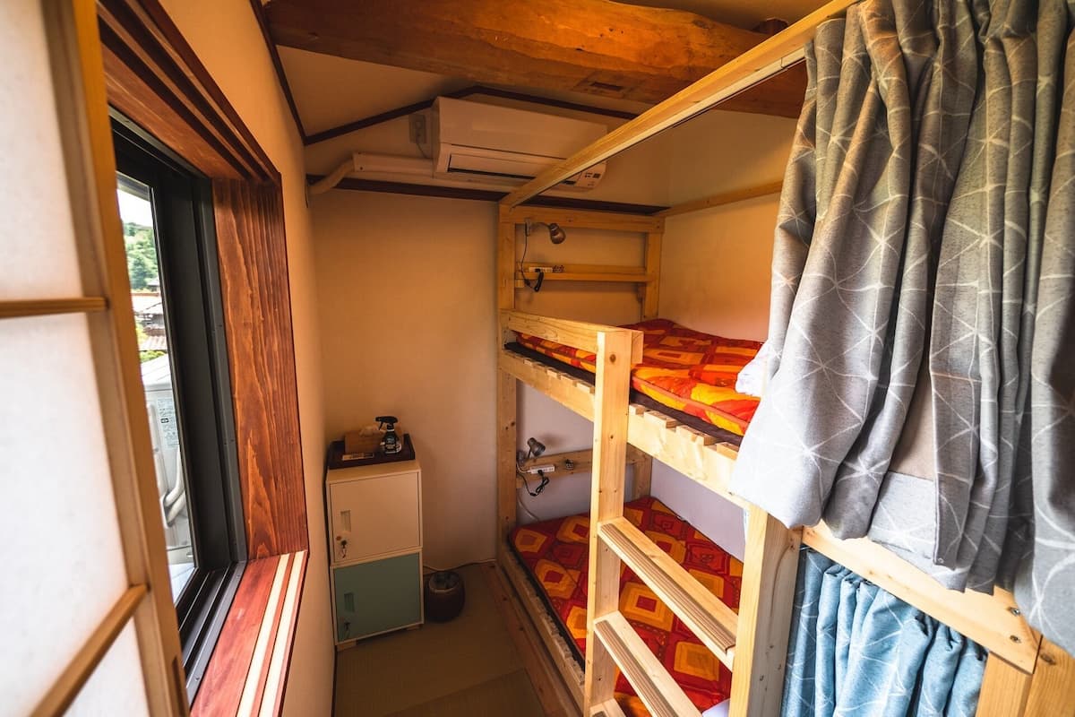 Um compartimento de trem compacto com beliches, uma kitchenette pequena e uma janela.