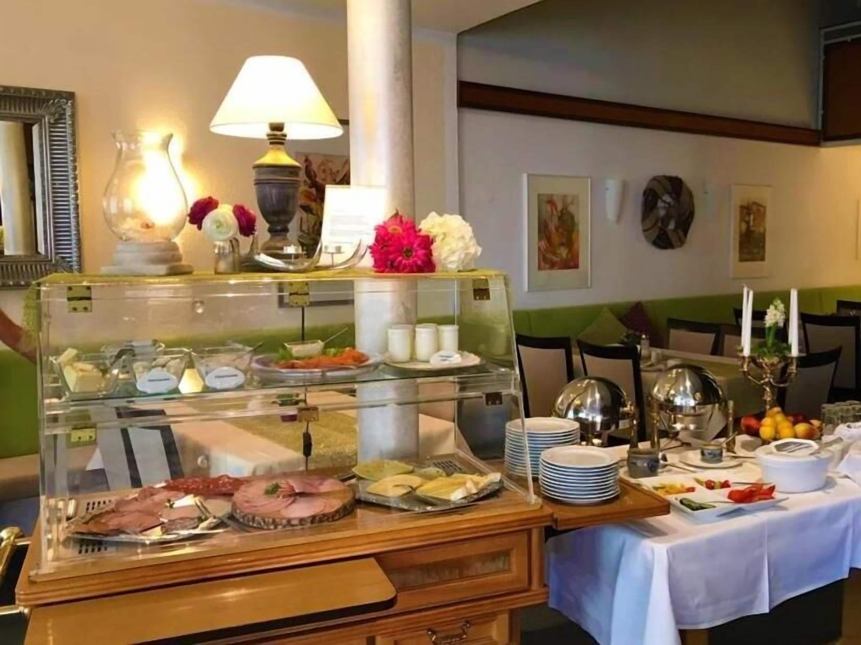 Uma mesa de buffet com diversos alimentos, uma lâmpada e um vaso decorativo.