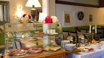 Uma mesa de buffet com diversos alimentos, uma lâmpada e um vaso decorativo.