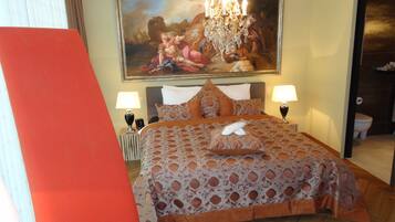 Quarto de hotel com uma cama grande, duas luminárias de cabeceira, um quadro sobre a cama e um candelabro.