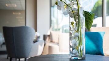 Um vaso transparente com flores brancas sobre uma mesa redonda em um espaço interior moderno.