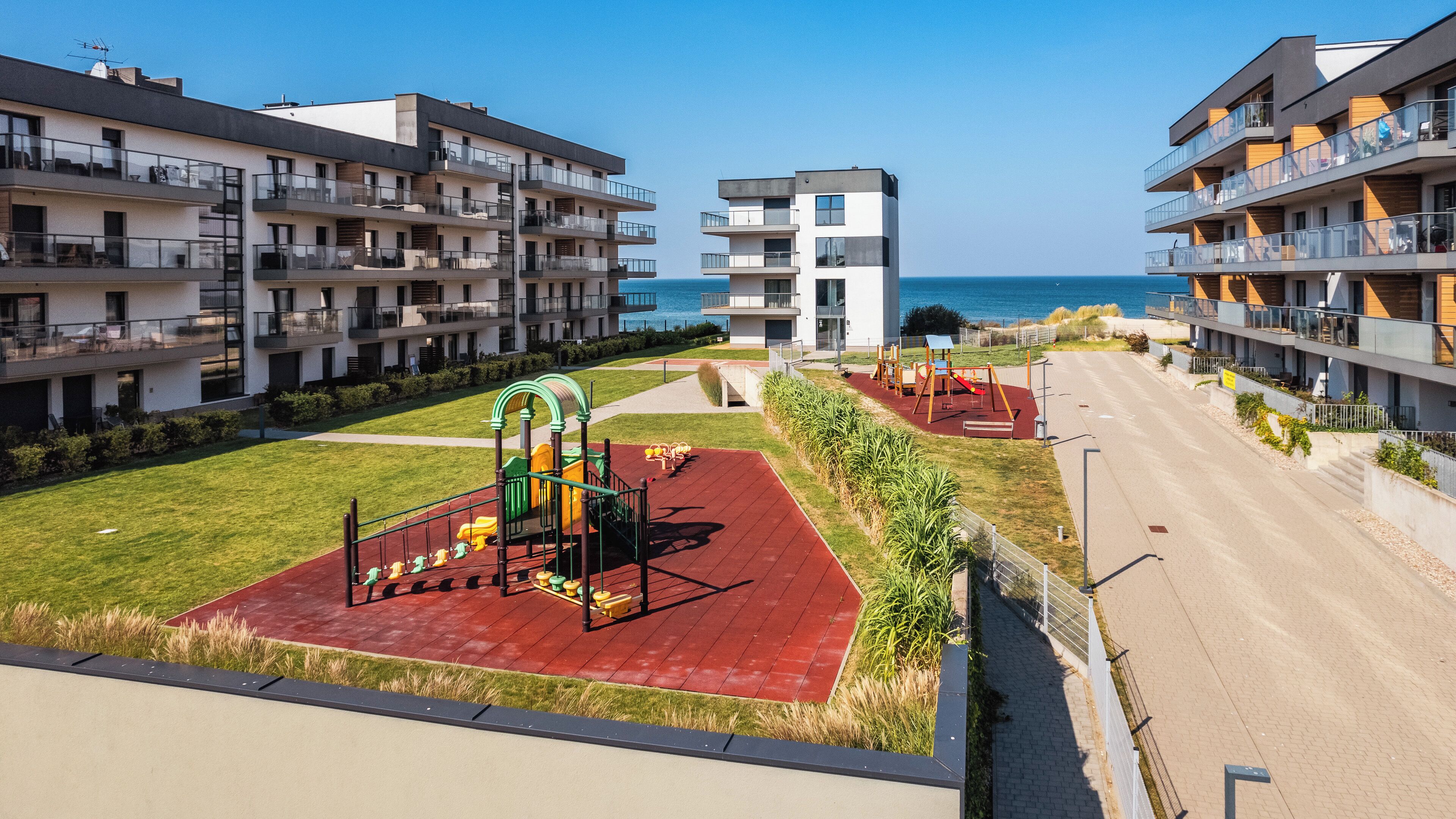 Um edifício residencial com varandas, parquinho infantil e vista para o mar.