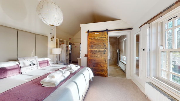 Quarto com uma cama grande, porta de madeira e vista para o exterior.