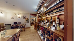 Um restaurante com móveis de madeira, um espaço para vinhos e uma cabeça de veado na parede.
