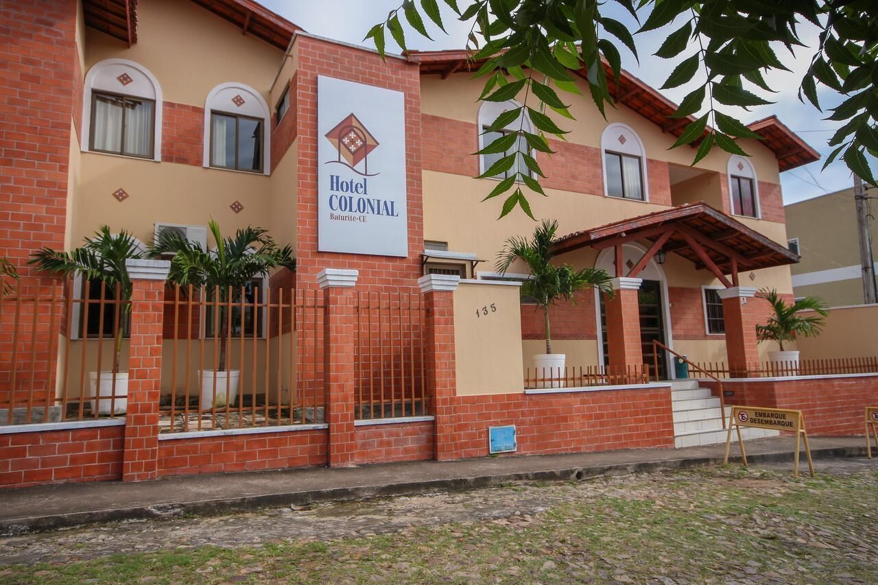 Hotel Colonial com fachada de tijolos, uma placa de identificação e entrada com portão.