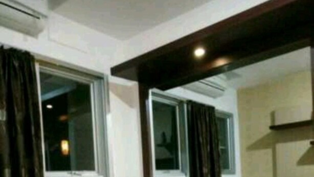 Um sofá bege numa sala de estar com uma janela grande e cortinas.