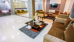 Uma sala de estar moderna com uma mesa de centro de vidro, sofás e uma televisão.