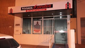Um edifício com uma placa indicando "POUSADA Executive" e entrada acessível para cadeiras de rodas.