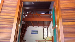 Quarto com teto de madeira, uma cama e um quadro na parede.