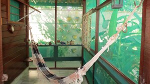 Uma rede em um quarto com vista para um jardim através de uma janela.