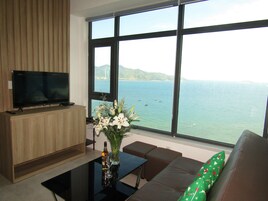 Apartamento superluxo, 2 quartos, cozinha americana, vista para a praia | Sala de estar | TV de tela plana 43 polegadas com canais a cabo, smart TV