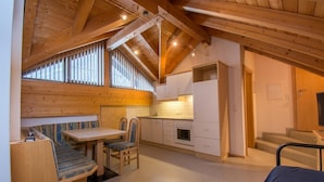 Um quarto acolhedor em estilo cabana, com teto de madeira, área de jantar com bancos e cozinha compacta.