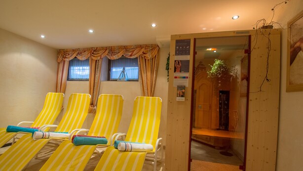 Quatro poltronas listradas de amarelo, uma porta de madeira com painel de vidro e uma pequena janela com cortinas.