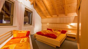 Um quarto aconchegante com duas camas de solteiro, teto de madeira e mesa de cabeceira com abajur.