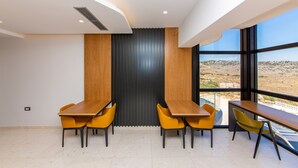 Uma sala de conferência moderna com uma grande mesa e cadeiras, vista para o deserto através de amplas janelas e uma parede de destaque em madeira.