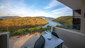Varanda com mesa e cadeiras com vista para um vale, um rio e colinas.