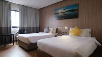 Quarto de hotel com duas camas, uma secretária e um quadro na parede.
