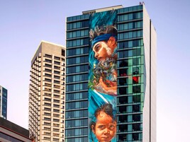 Um edifício alto com um grande mural na fachada.