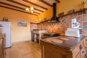 Uma cozinha com painel de azulejos, fogão, cafeteira e armários de madeira.