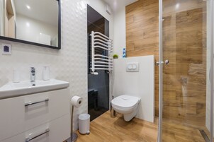 Um banheiro moderno com pia branca, vaso sanitário e box de vidro.