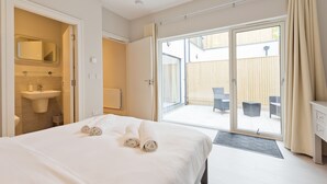 Quarto de hotel com cama, banheiro e porta de vidro deslizante para um pátio externo.