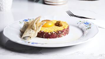 Um prato com comida, um pote e um garfo sobre uma mesa.