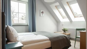 Quarto com cama, escrivaninha, cadeira e janelas no teto.