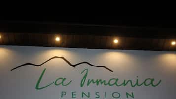 Uma placa com o texto 'La Irmania Pension' e o contorno de uma montanha.