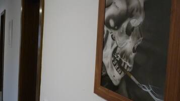 Um corredor com uma obra de arte emoldurada retratando um crânio fumando um cigarro.