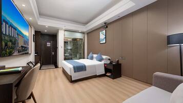 Quarto de hotel moderno com cama, escrivaninha, cadeira e televisão.