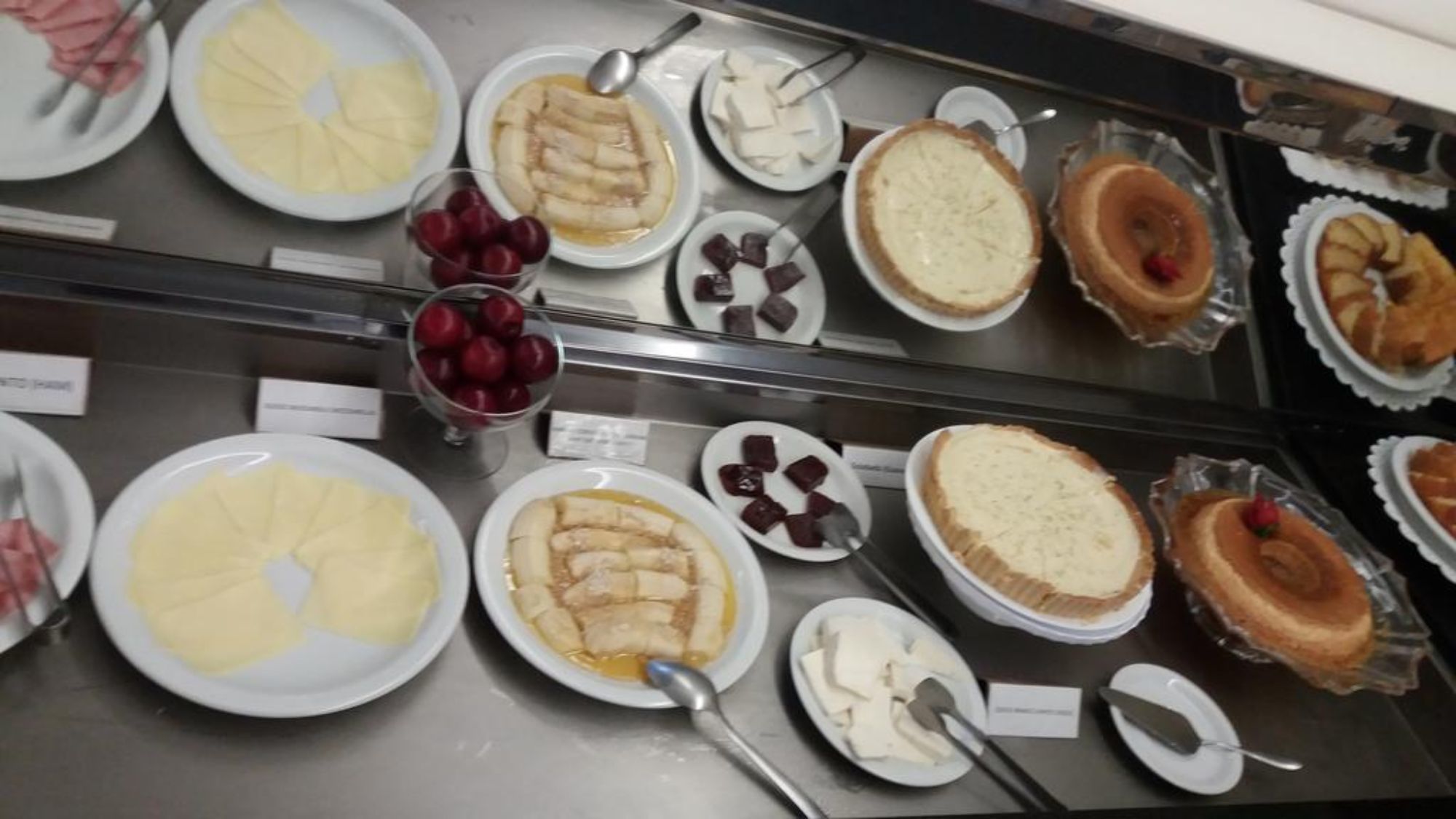 Vitrine com diversos doces, incluindo bolos, tortas e frutas.