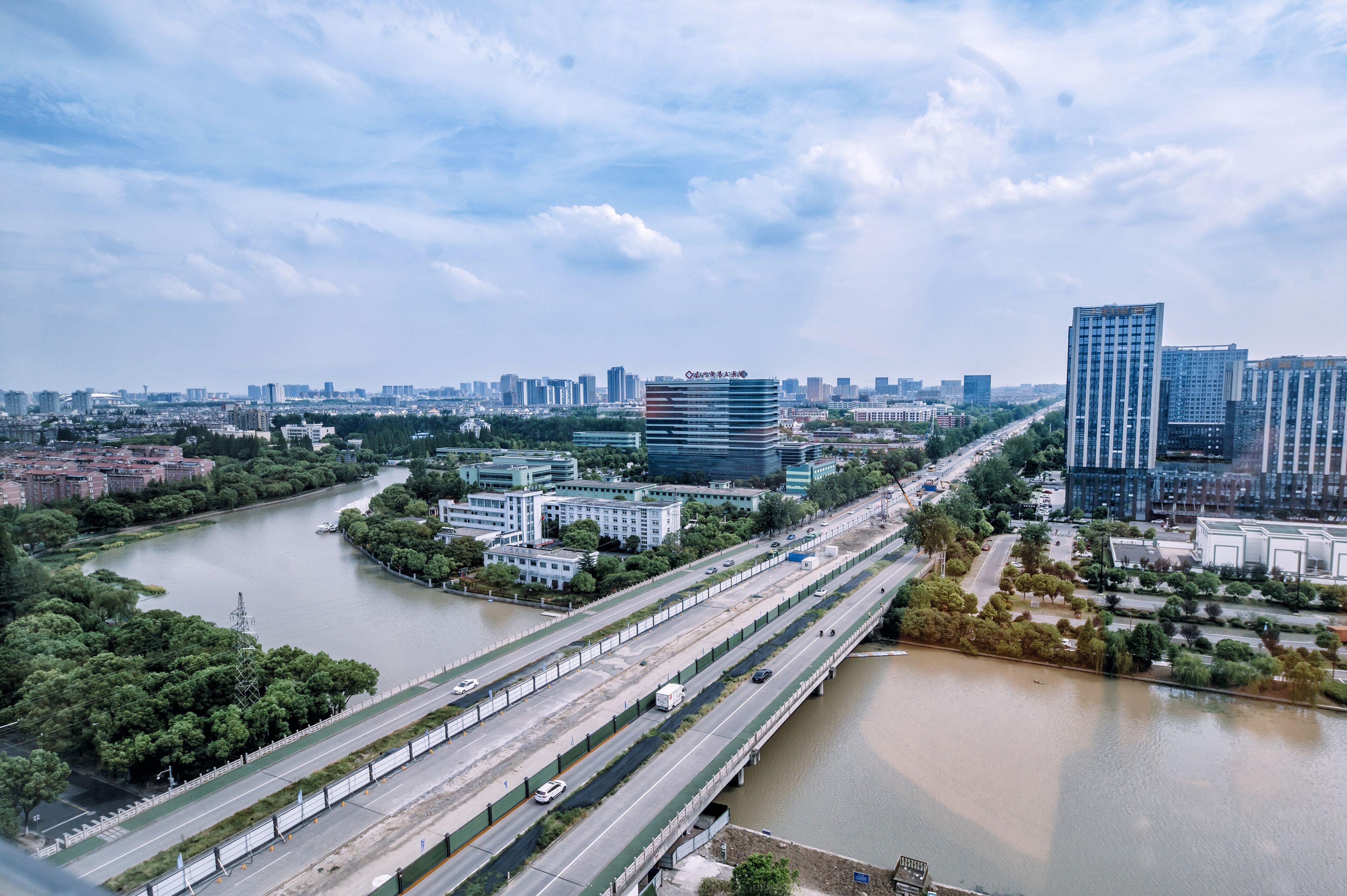 Paisagem urbana com um rio, edifícios modernos e uma autoestrada.