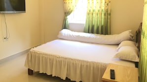 Quarto com cama, televisão na parede e mesa de cabeceira com controle remoto.