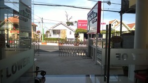 Vista da rua com uma entrada gradeada, um edifício branco com uma placa vermelha e uma placa indicando 'Pull In'.