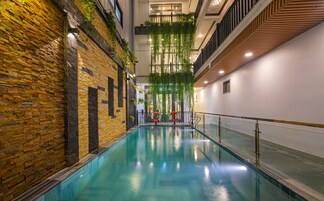 Piscina interior moderna com uma parede de pedra de um lado e guarda-corpo de vidro do outro.