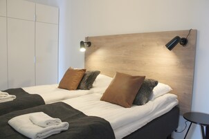 Quarto de hotel com duas camas, uma cabeceira de madeira e abajures.