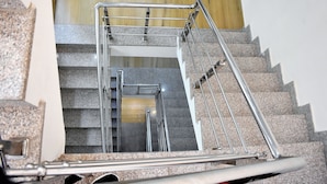 Uma escadaria moderna com grades de metal e degraus de granito.